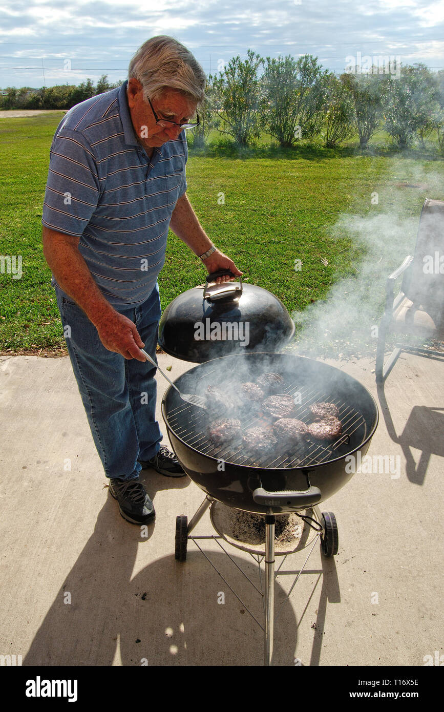 Man cooking hamburger patties on black grill Stock Photo - Alamy