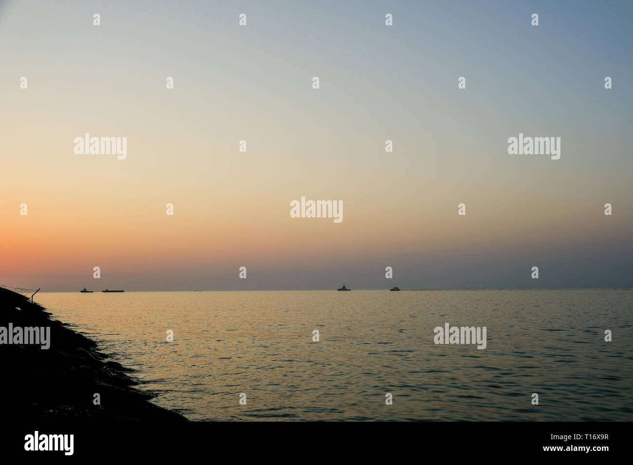 Distant Cargo Ships in a calm sea at evening Stock Photo - Alamy