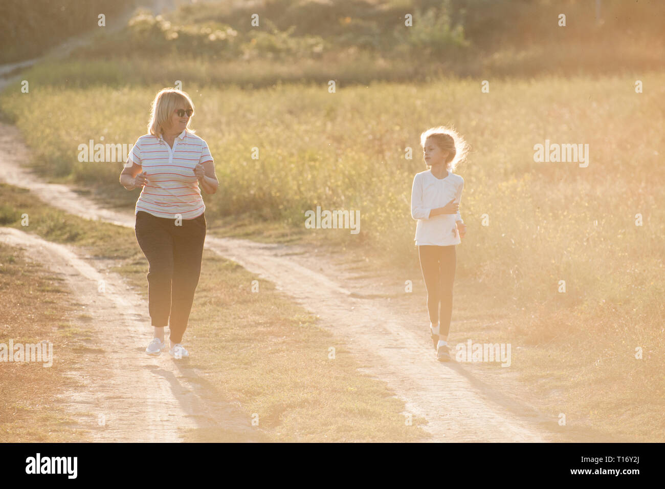 active fat grandmother walking outdoors together with little thin girl ...