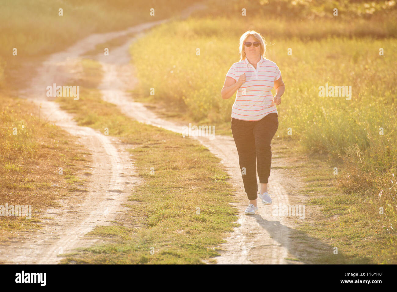 active fat adult woman running along track outdoor leisure workout ...