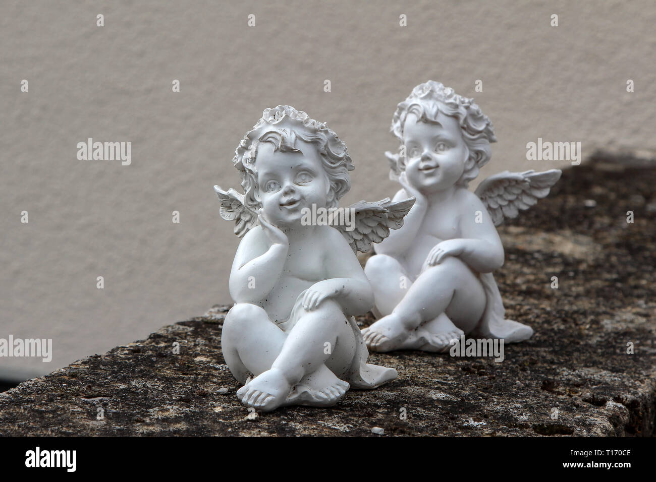 Two miniature angels on a stone wall Stock Photo - Alamy