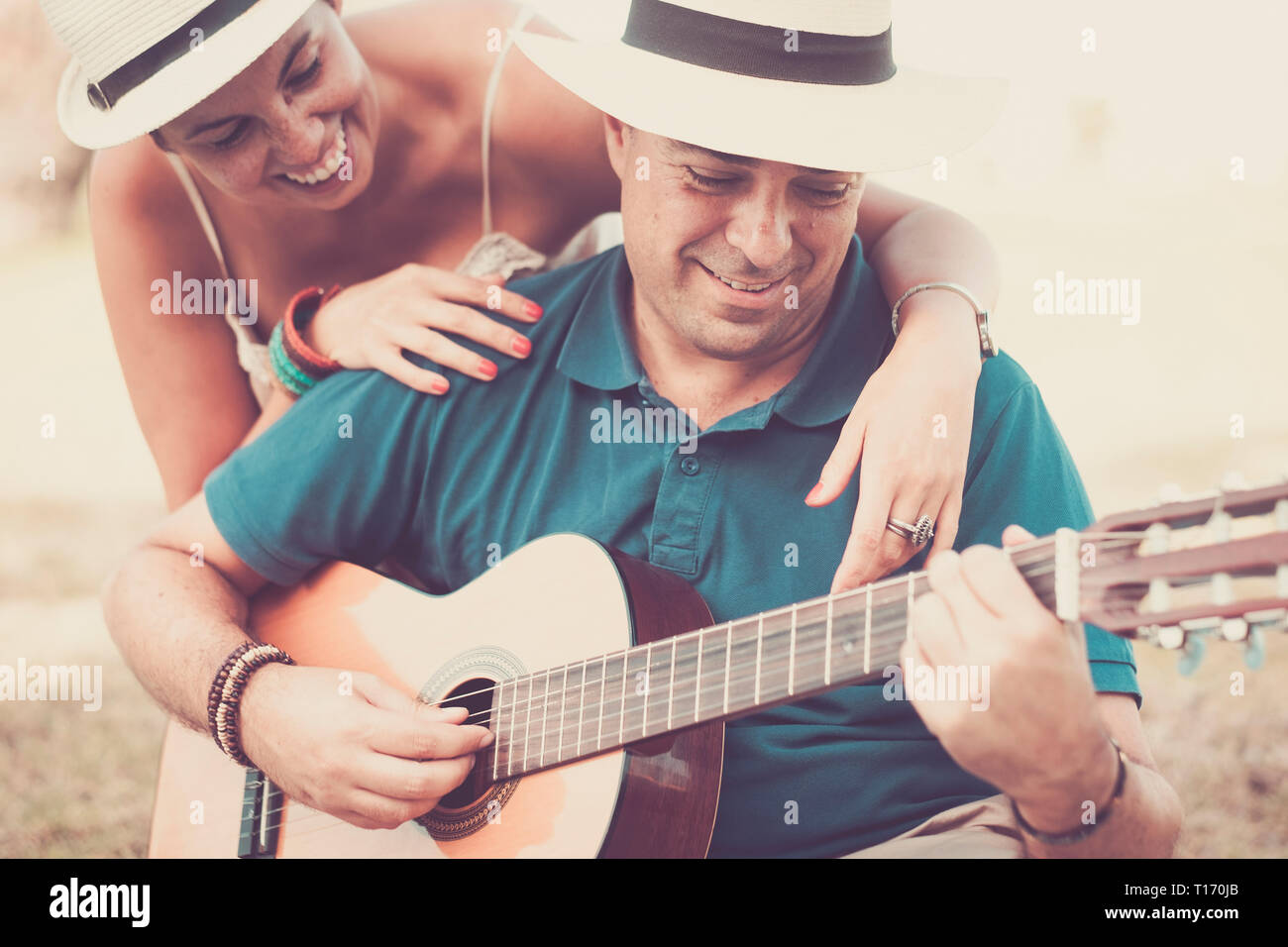 Romantic adult couple in love play together a guitar and enjoy the ...