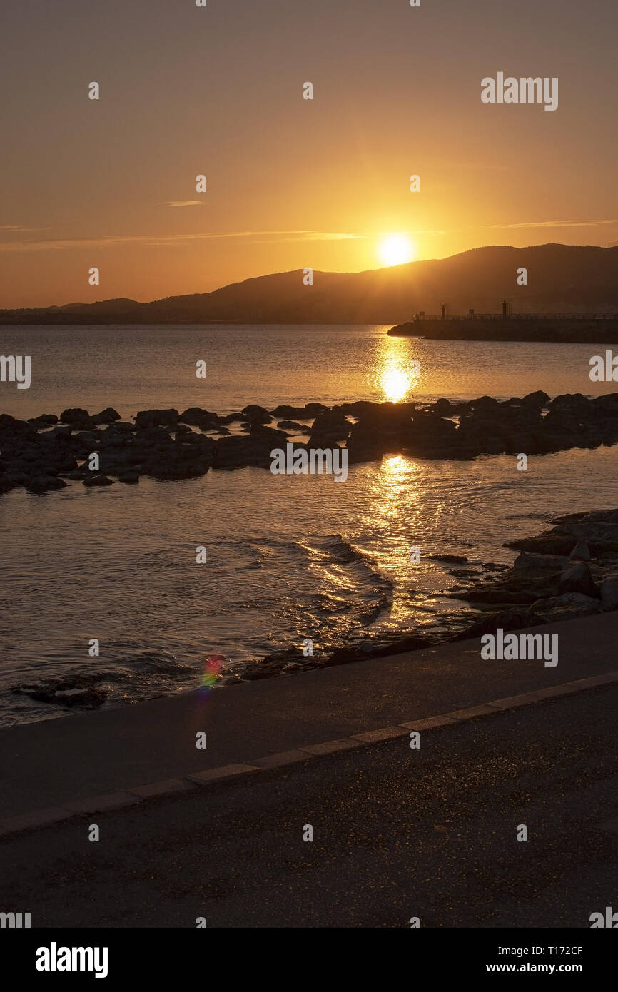 Beautiful sunset over mountains and ocean with string of rocks in ...