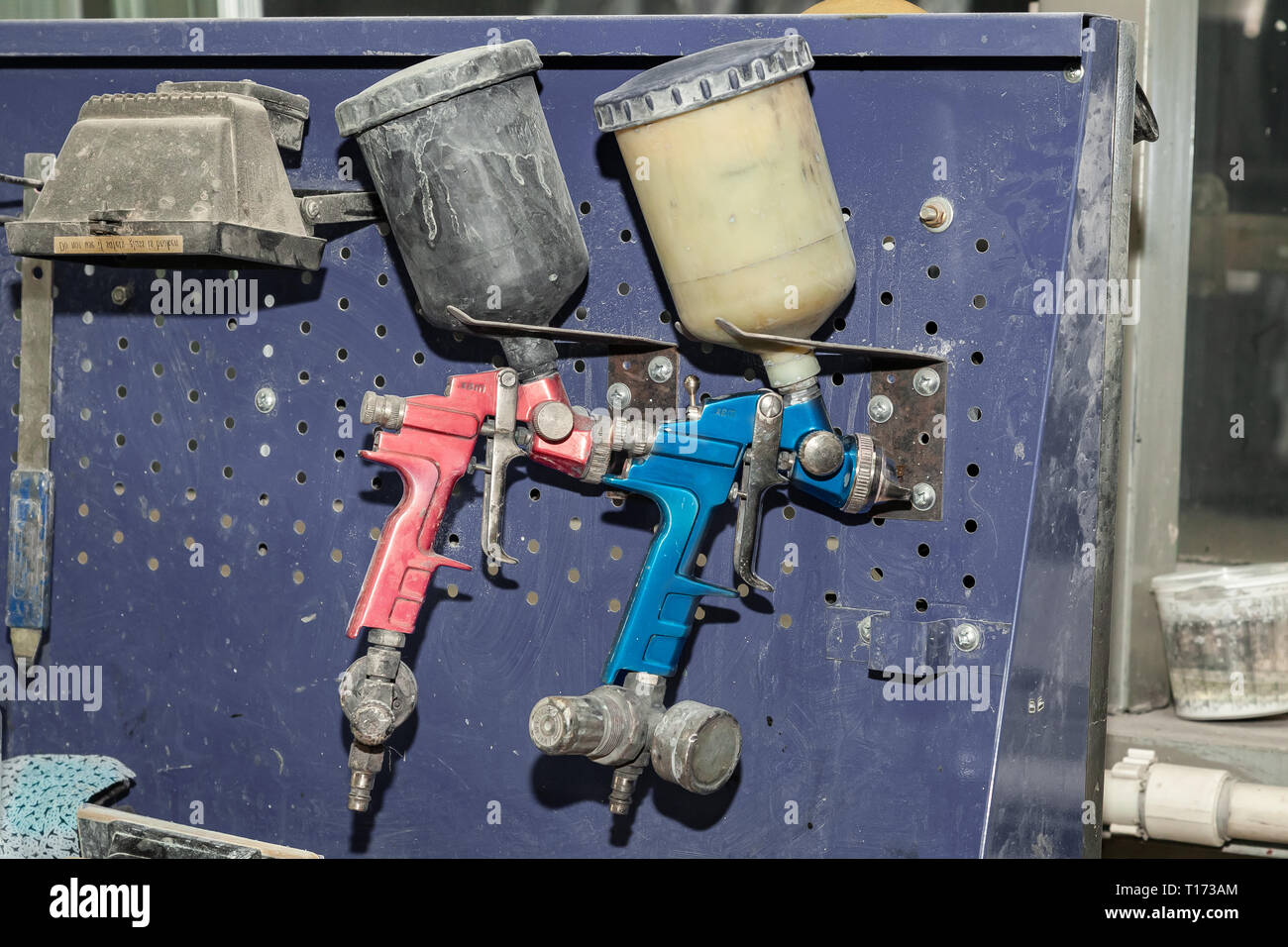 Two body paint gun sprayer red and blue installed on a workbench in a ...