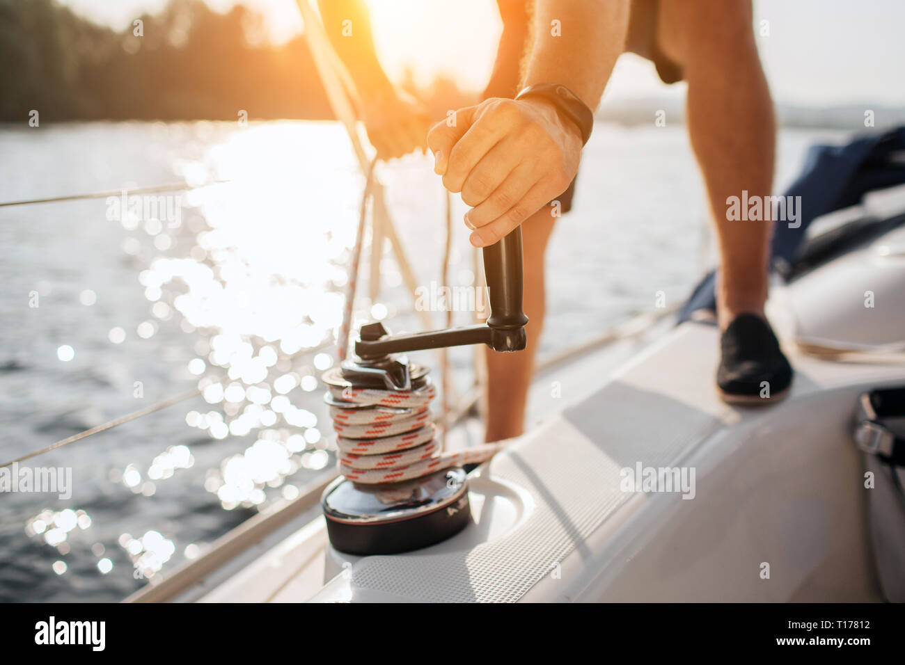 Close up of sailor winds aroung rope by using handle for coiling. He ...