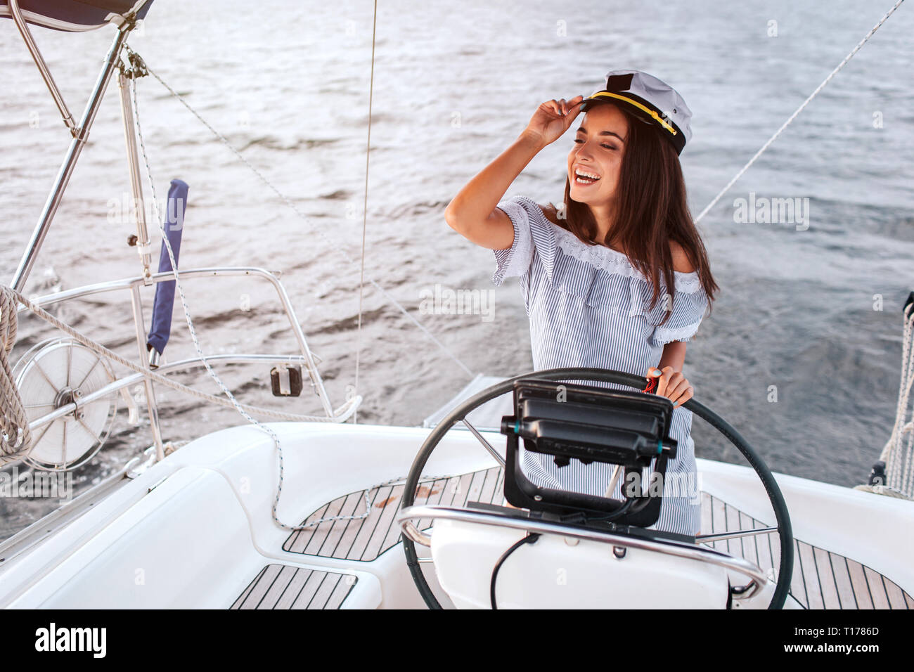 Beautiful model stands in front of rudder and uses it. She holds hand ...