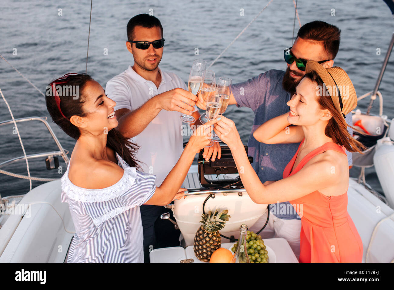 Two couples stand in front of each other and cheers with glasses of ...