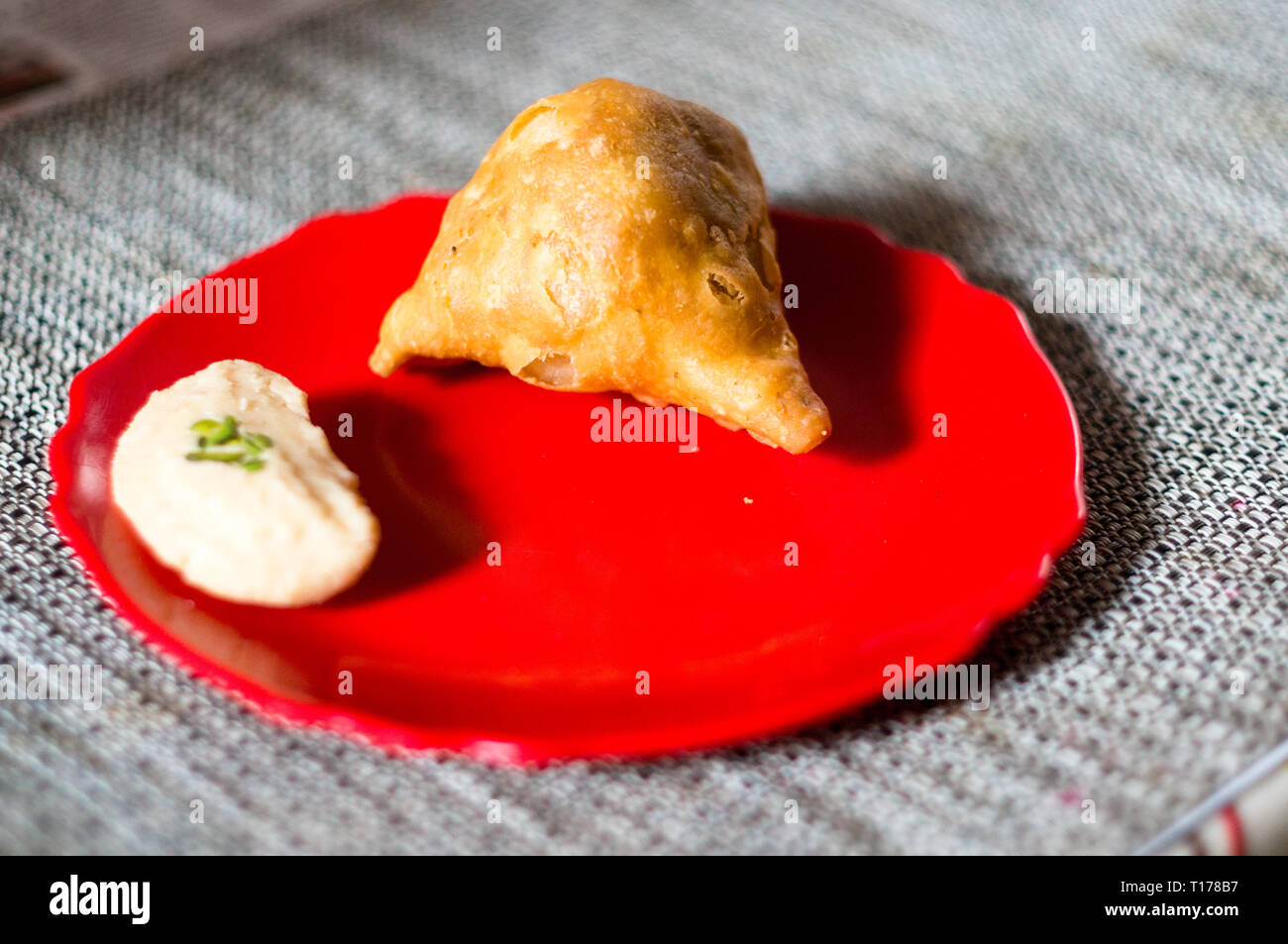 Samosa, peda barfi on red plate and woven mat, typical indian snack ...
