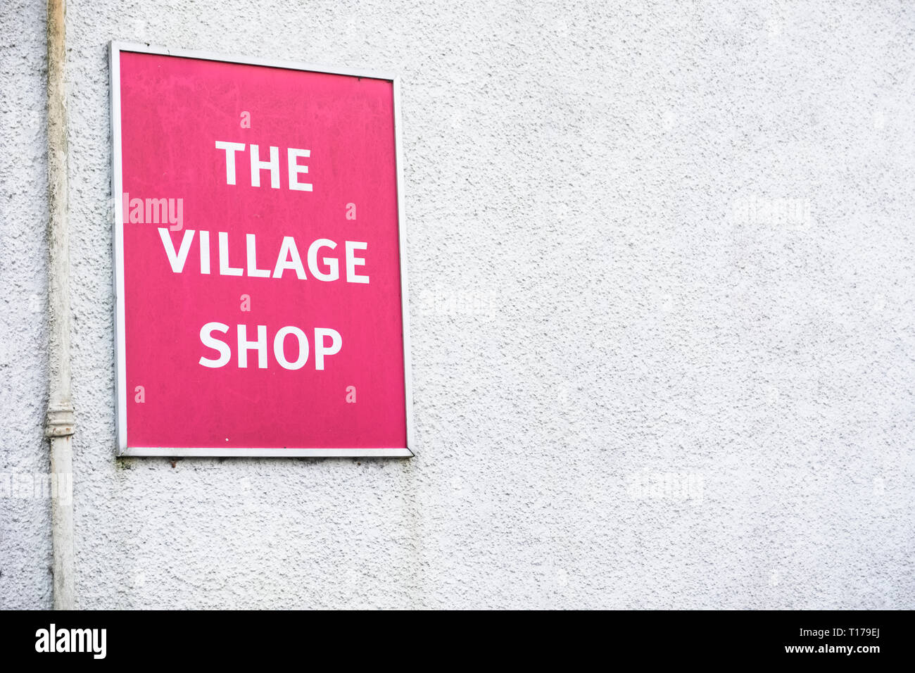 Village shop sign red on white wall background Stock Photo - Alamy