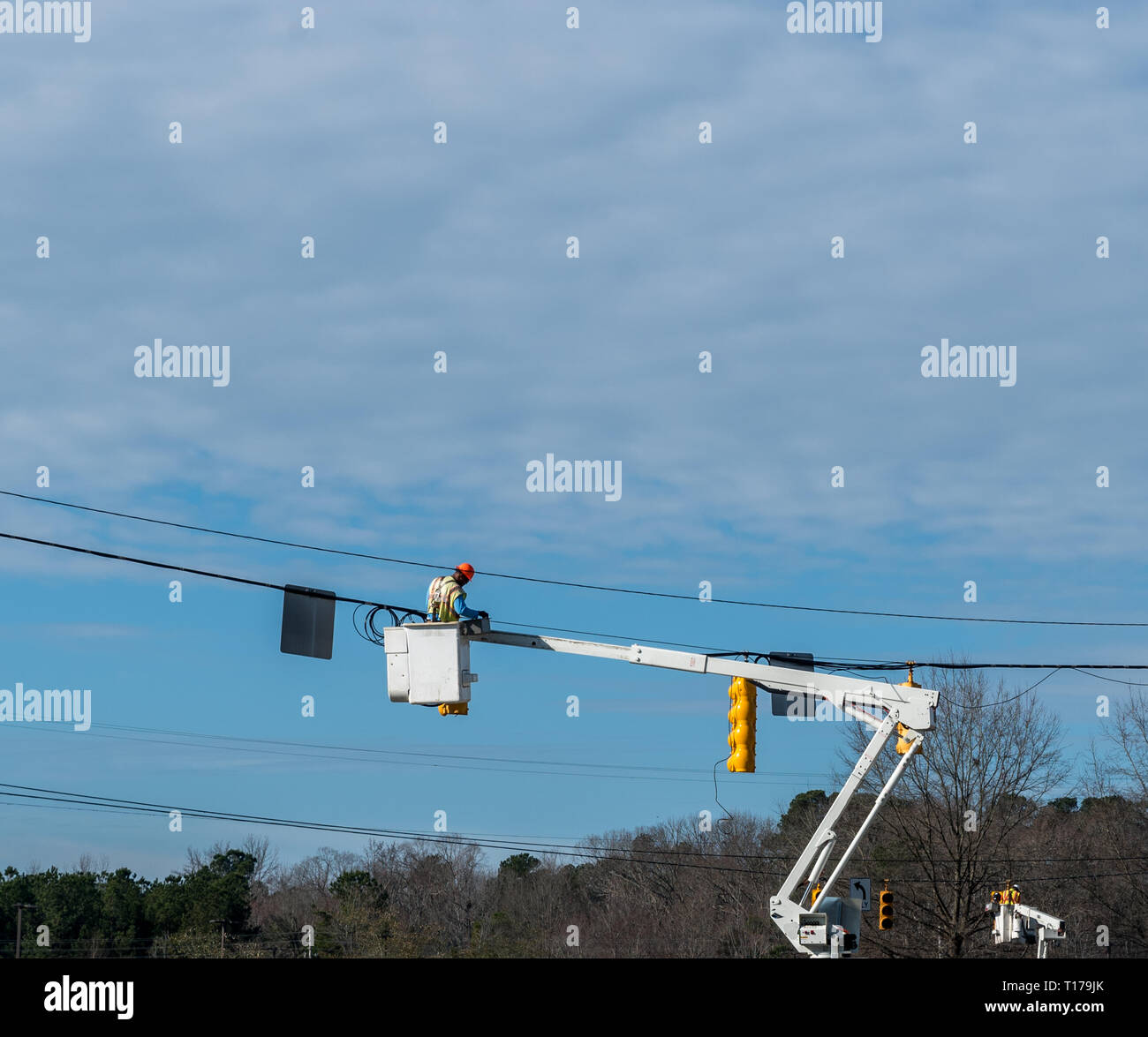 Power company worker in bucket above road repairing traffic light Stock ...