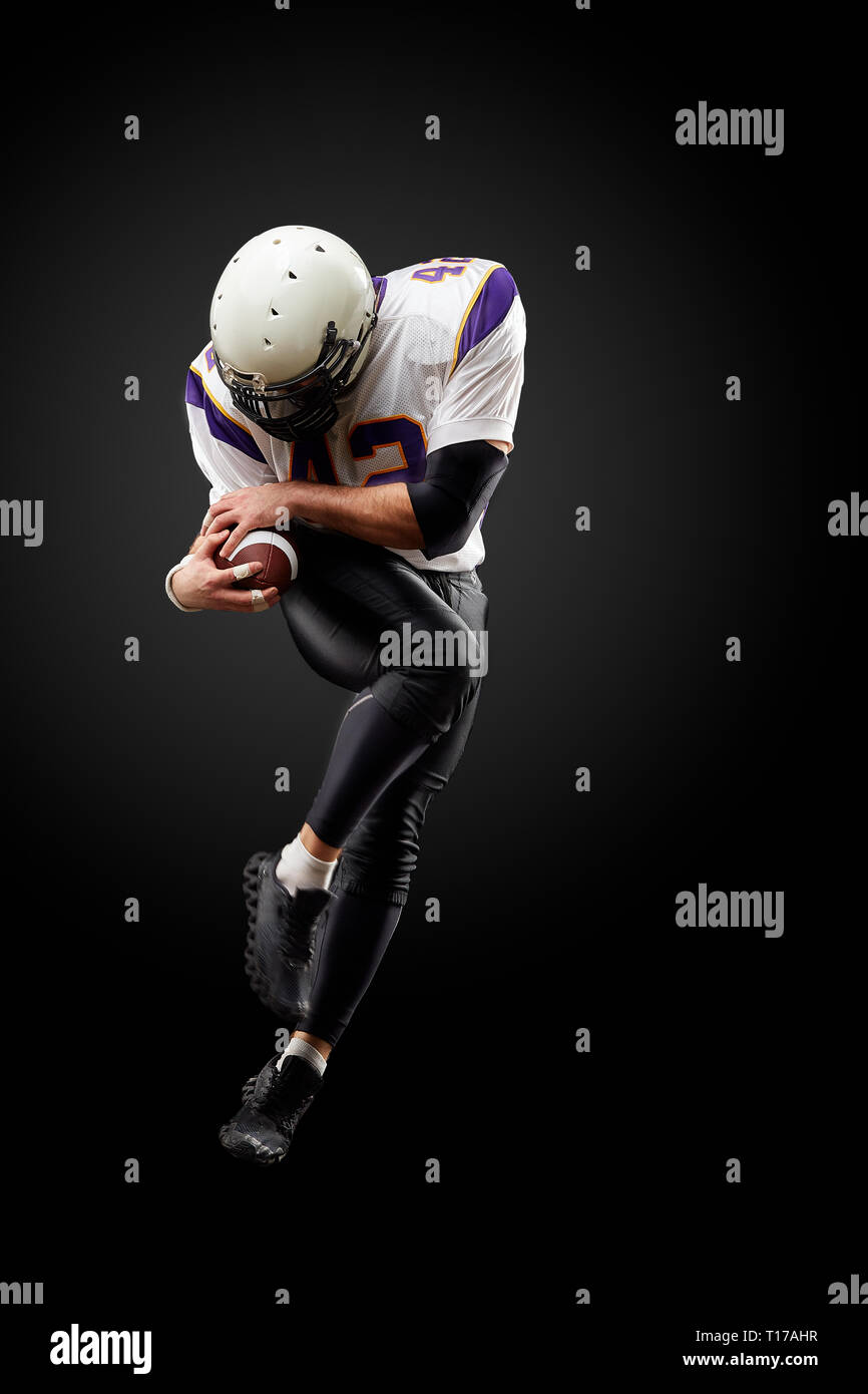 American football player in a jump with a ball on a black background ...
