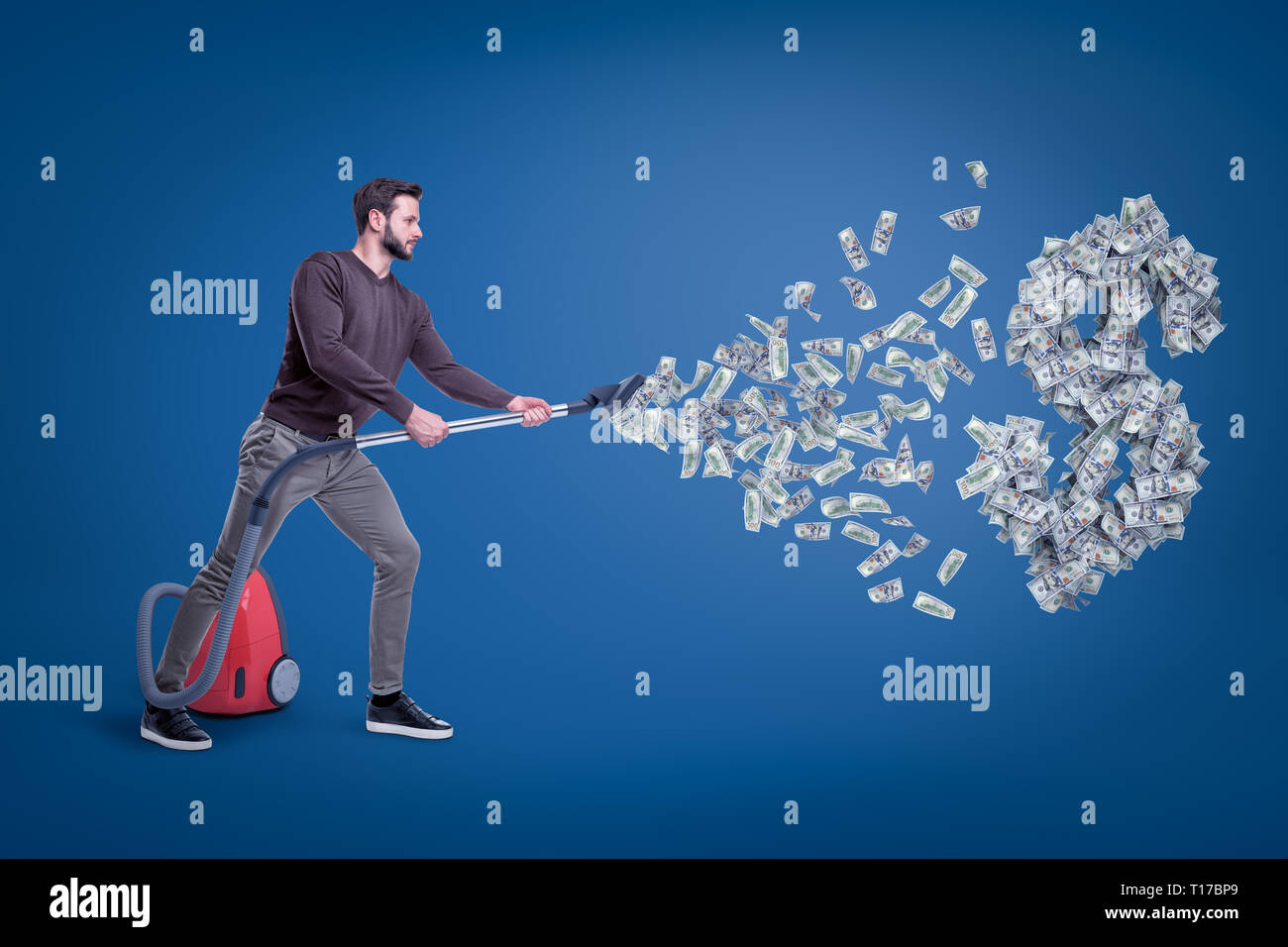 Side view of man in casual clothes hoovering up dollars and big dollar ...