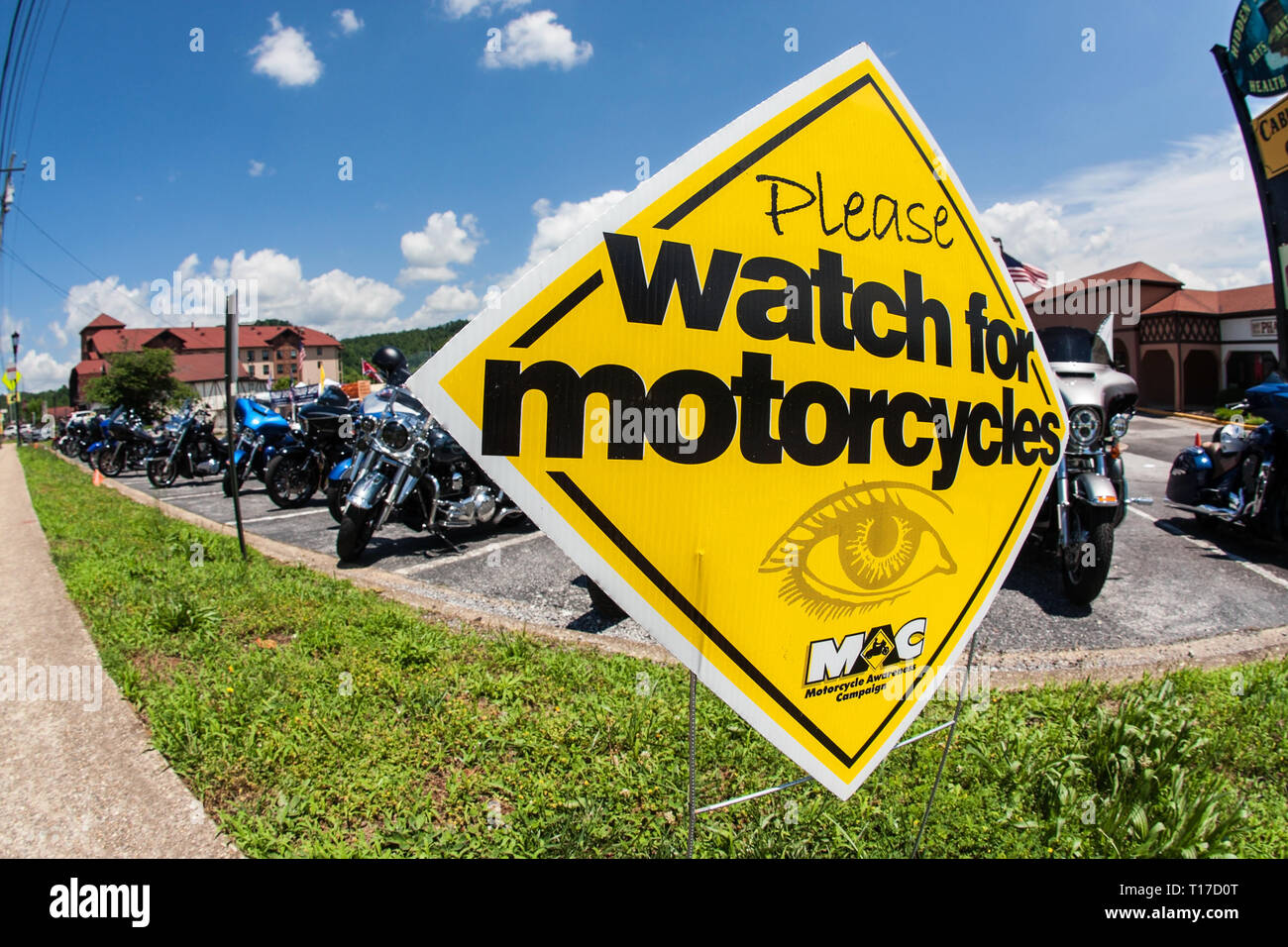 A sign warning people to watch for motorcycles, sits in front of a row ...