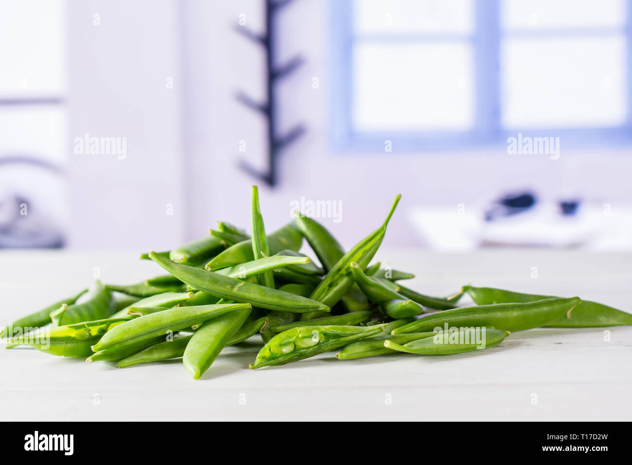 Lot of whole green sugar snap pea pods stack with blue window in a ...