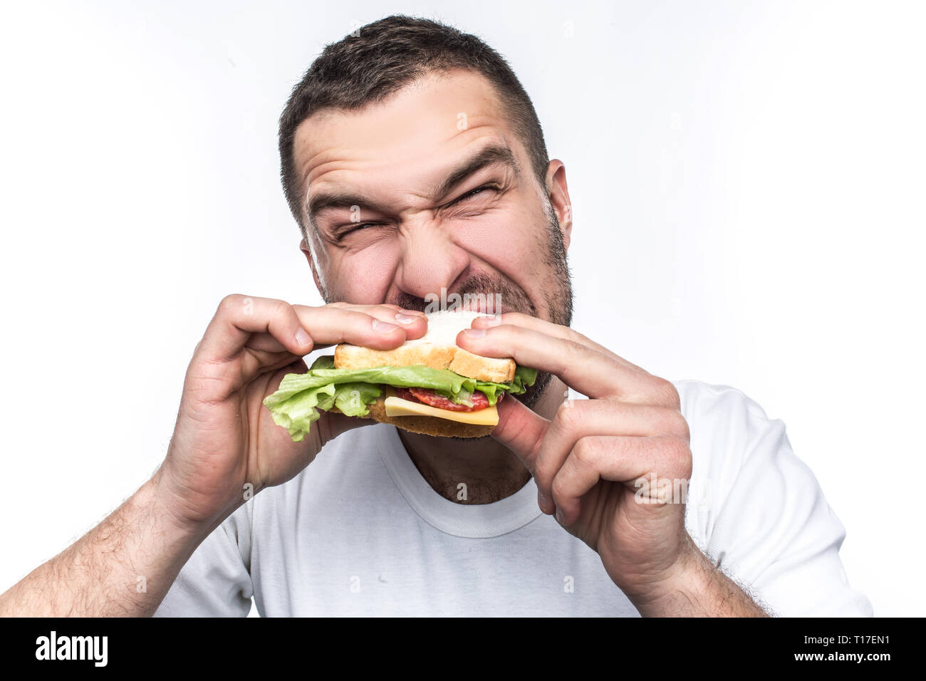 Funny and hungry guy is eating some fast food. He is hungry like a wolf ...
