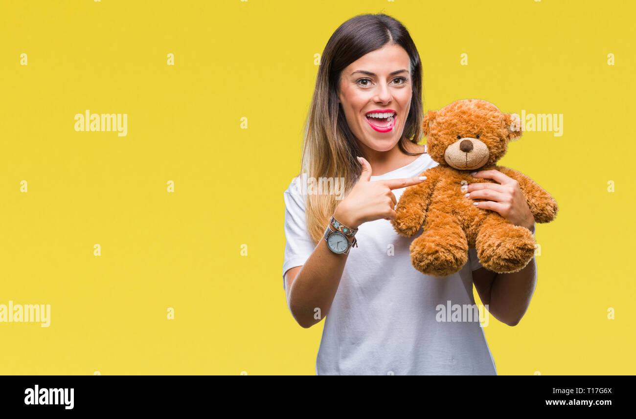 Young beautiful woman holding teddy bear plush over isolated background ...