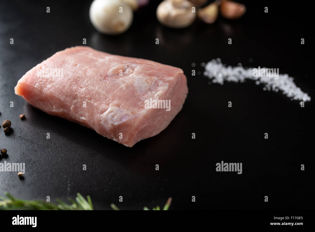 Portion of lean tender raw pork with seasoning, fresh herbs and cooking ...