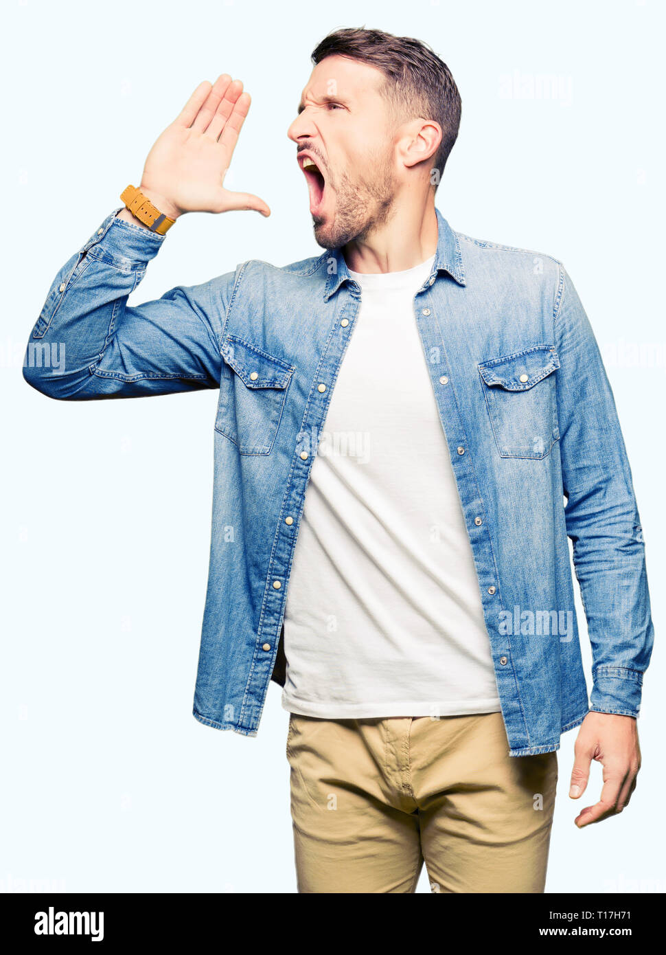 Handsome man with blue eyes and beard wearing denim jacket shouting and ...