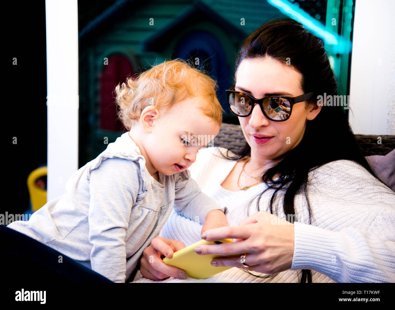 mother and daughter sharing mobile phone as she gets engrossed with new ...