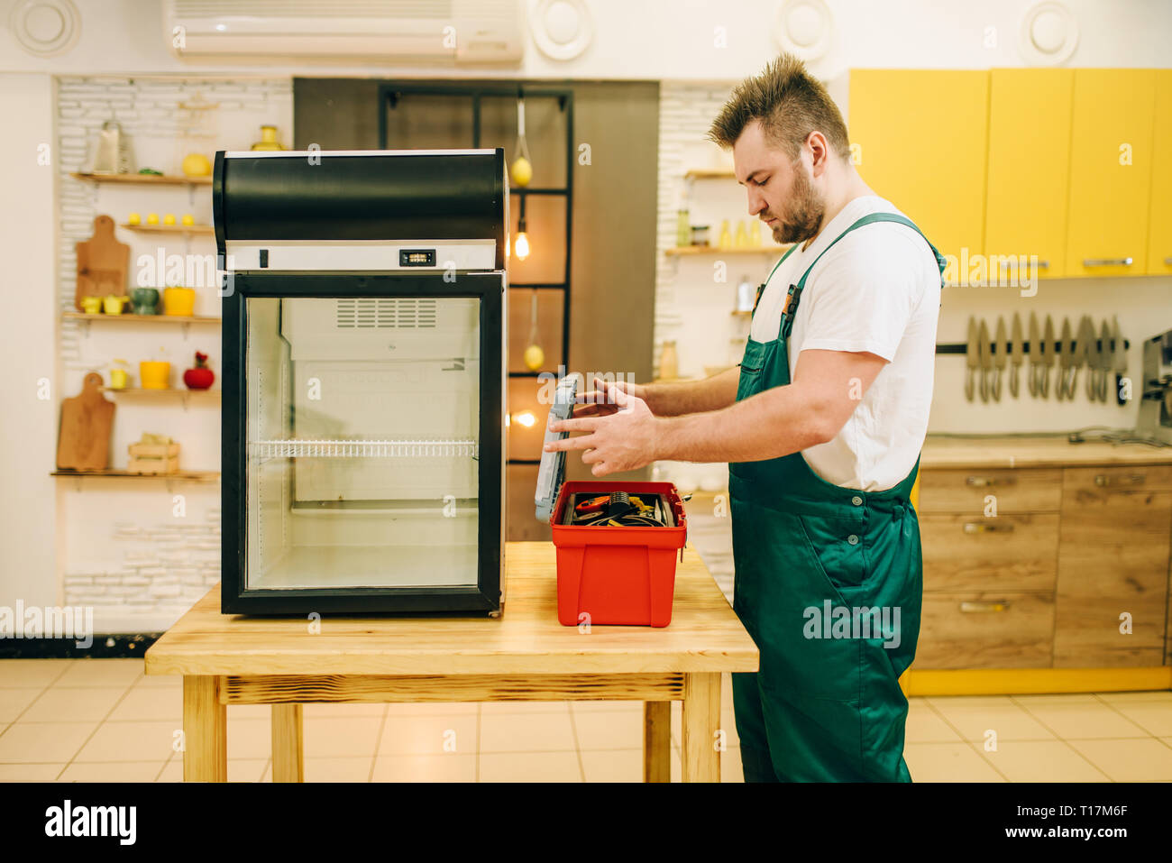 Worker with toolbox repair refrigerator at home Stock Photo - Alamy