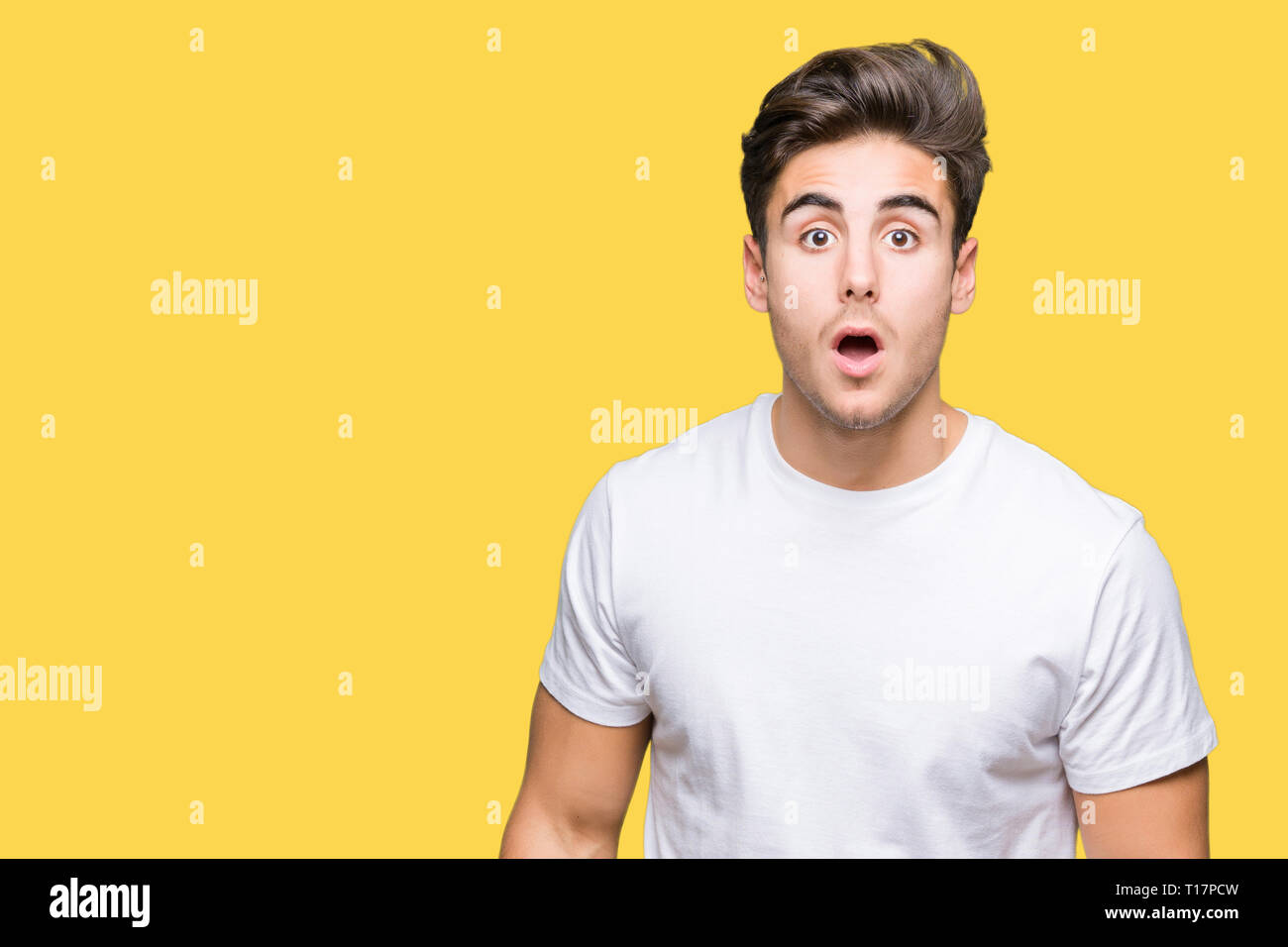 Young handsome man wearing white t-shirt over isolated background afraid and shocked with ...