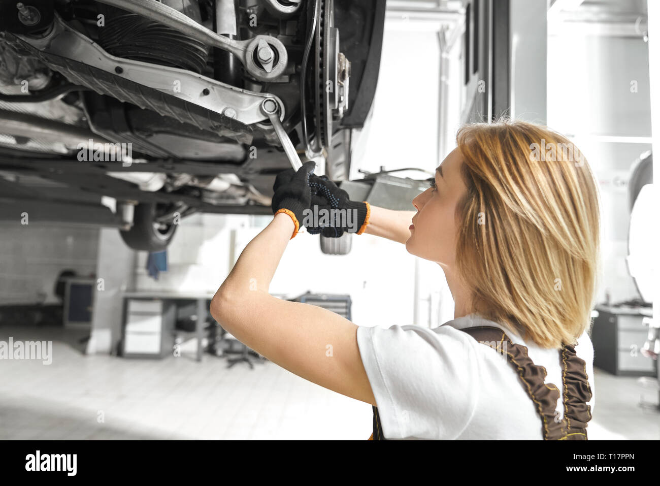 Blonde woman working as mechanic in autoservice, repairing car ...