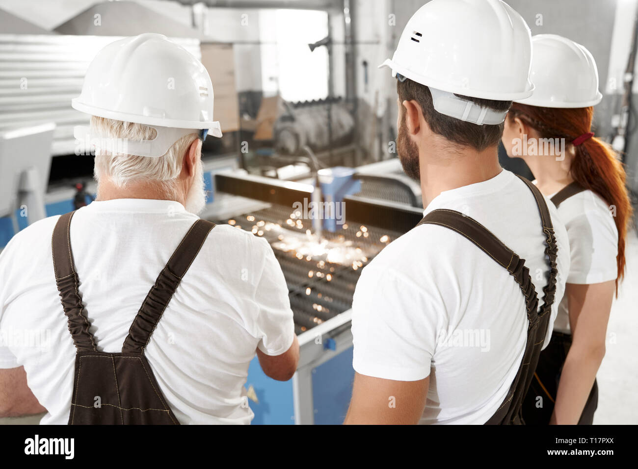 Back view of three engineers observing process of plasma laser cutting ...