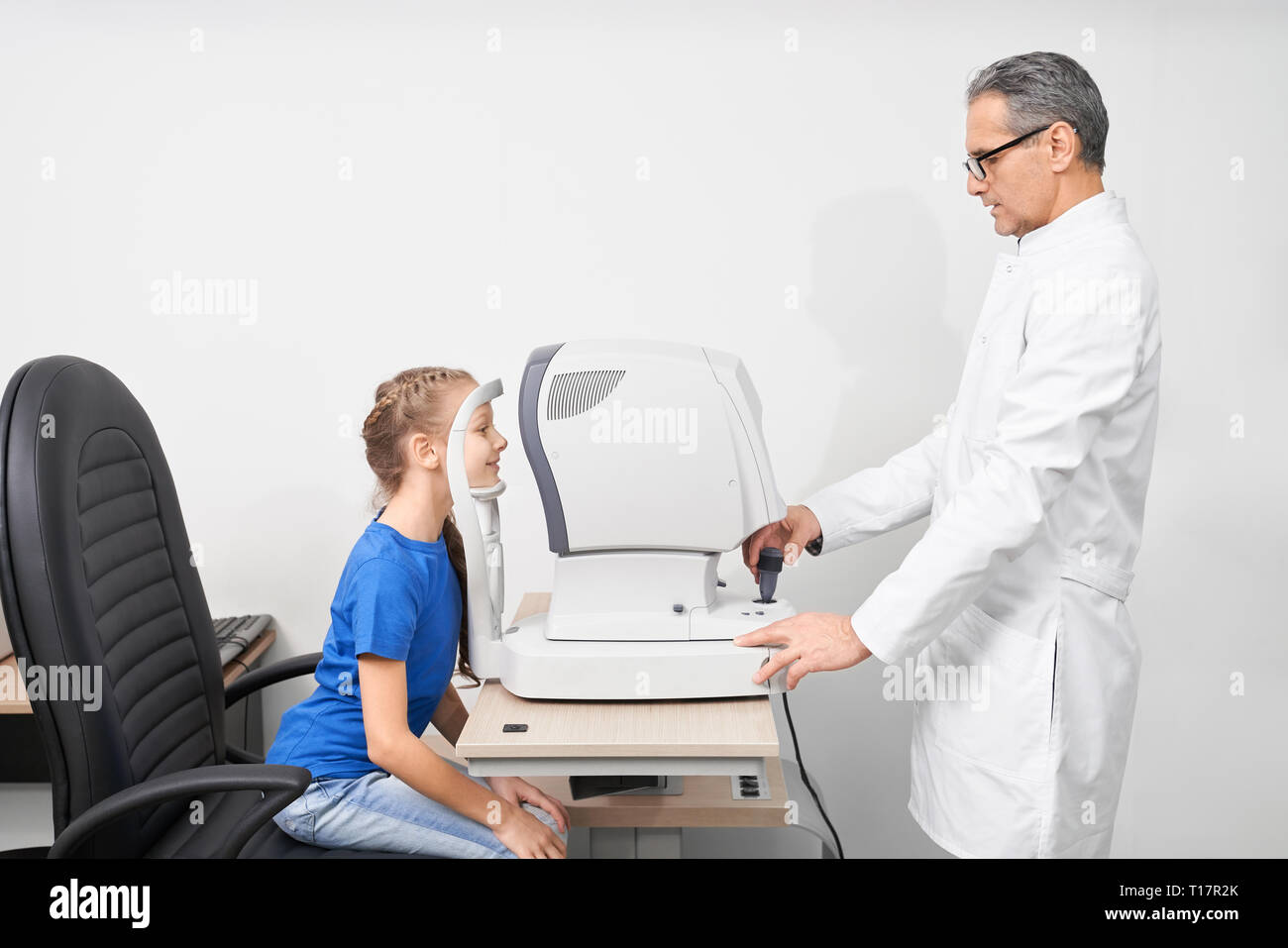 Doctor optometrist examining eyesight of young patient in optician ...