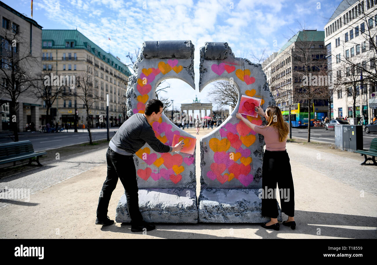 Berlin, Germany. 24th March 2019. A young man and a young woman spray ...
