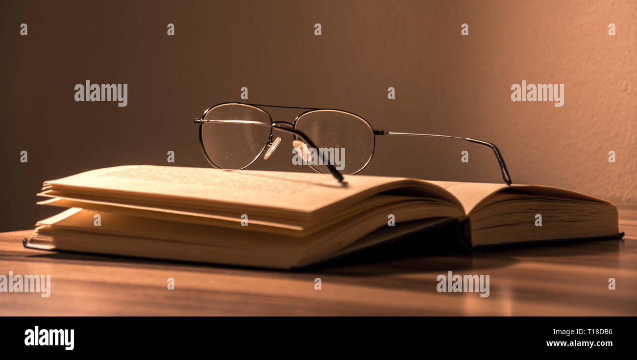 Close up of glasses laying on a open book Stock Photo - Alamy