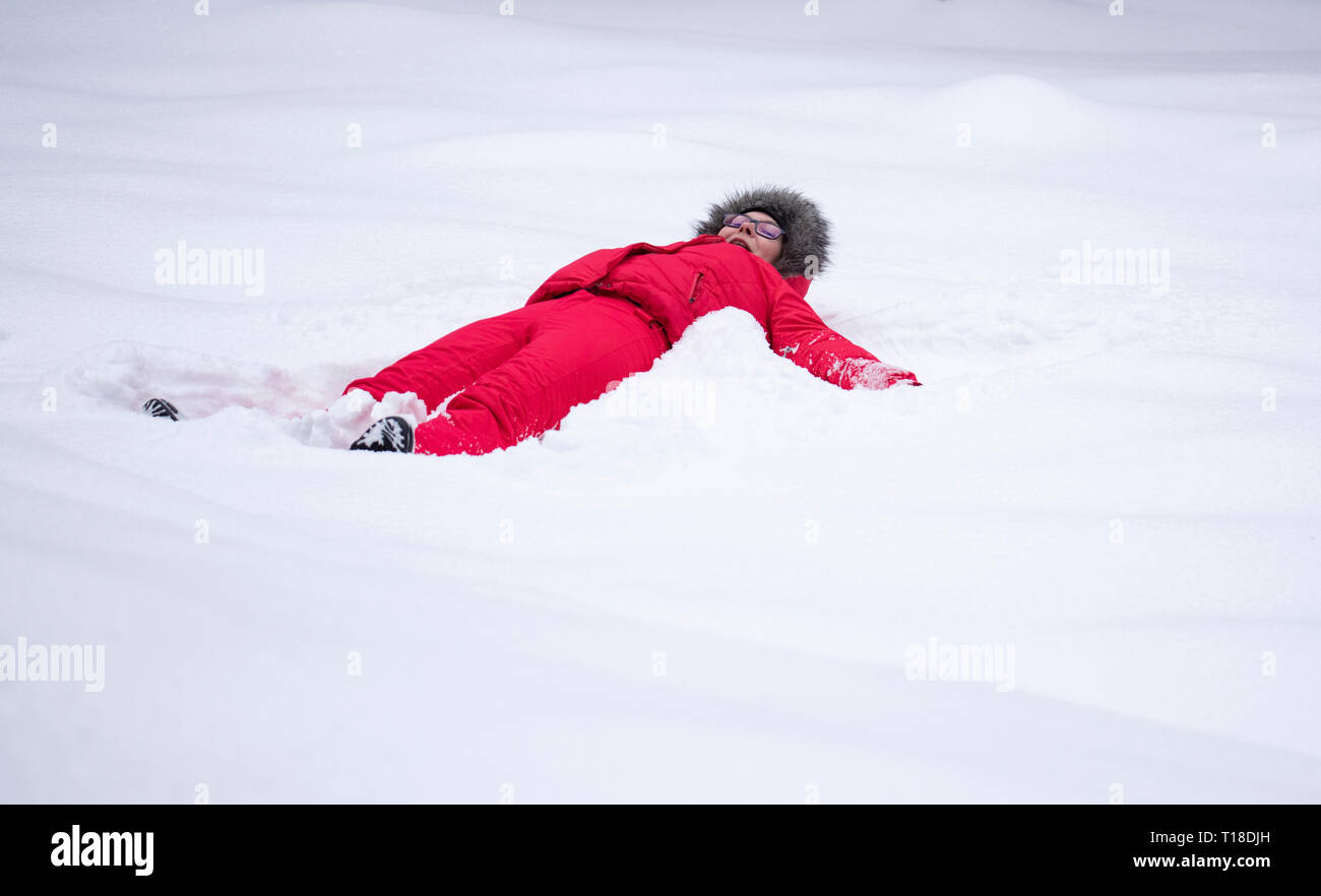 Girl in the snow making a snow angel enjoying the winter. Fun activity ...