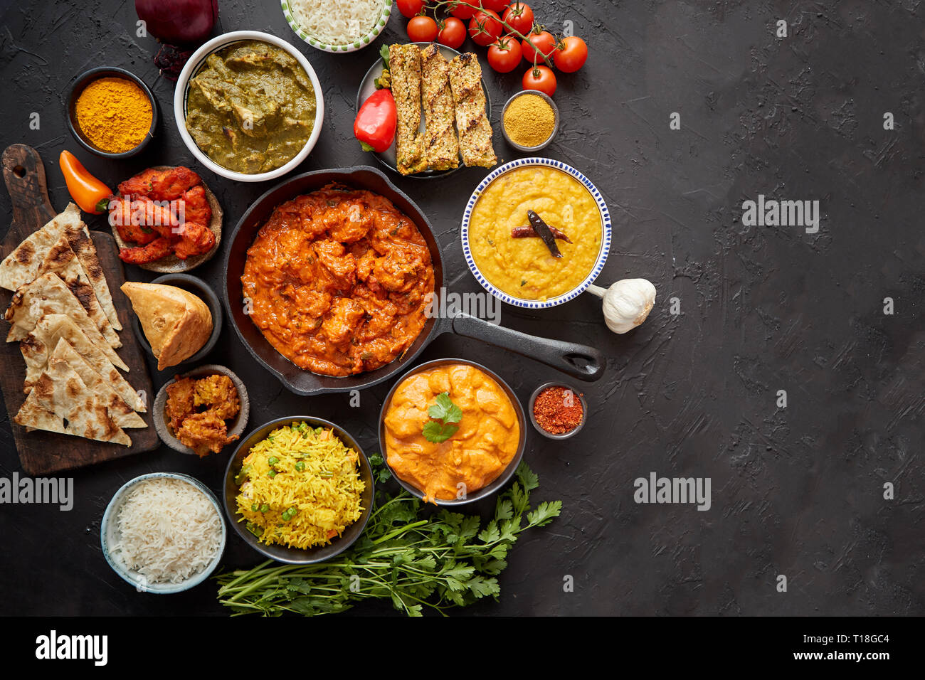 Composition of Indian cuisine in ceramic bowls on black stone table ...