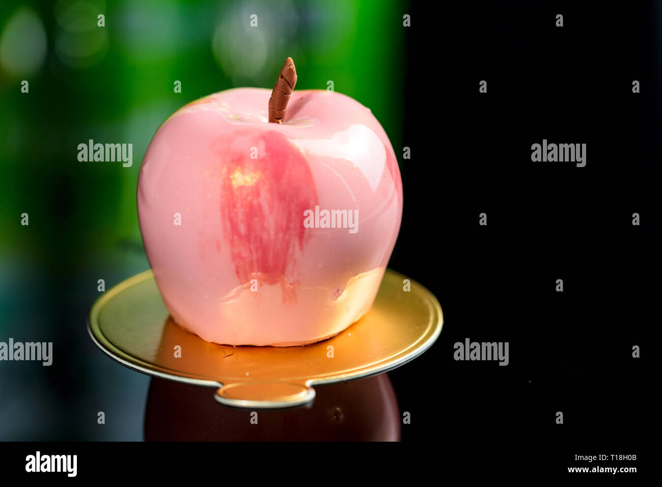 Trendy pink mirror glazed mousse cake in shape of apple, on dark ...