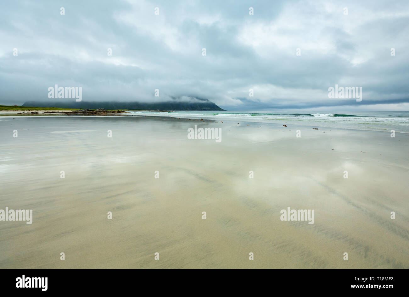 Summer misty and cloudy beach view with cloud reflections in wave water ...