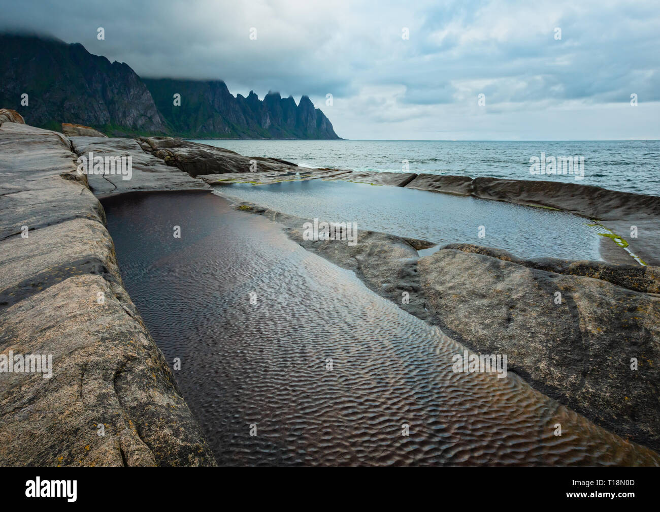 Stony beach with tidal baths at Ersfjord, Senja, Norway. Summer polar ...