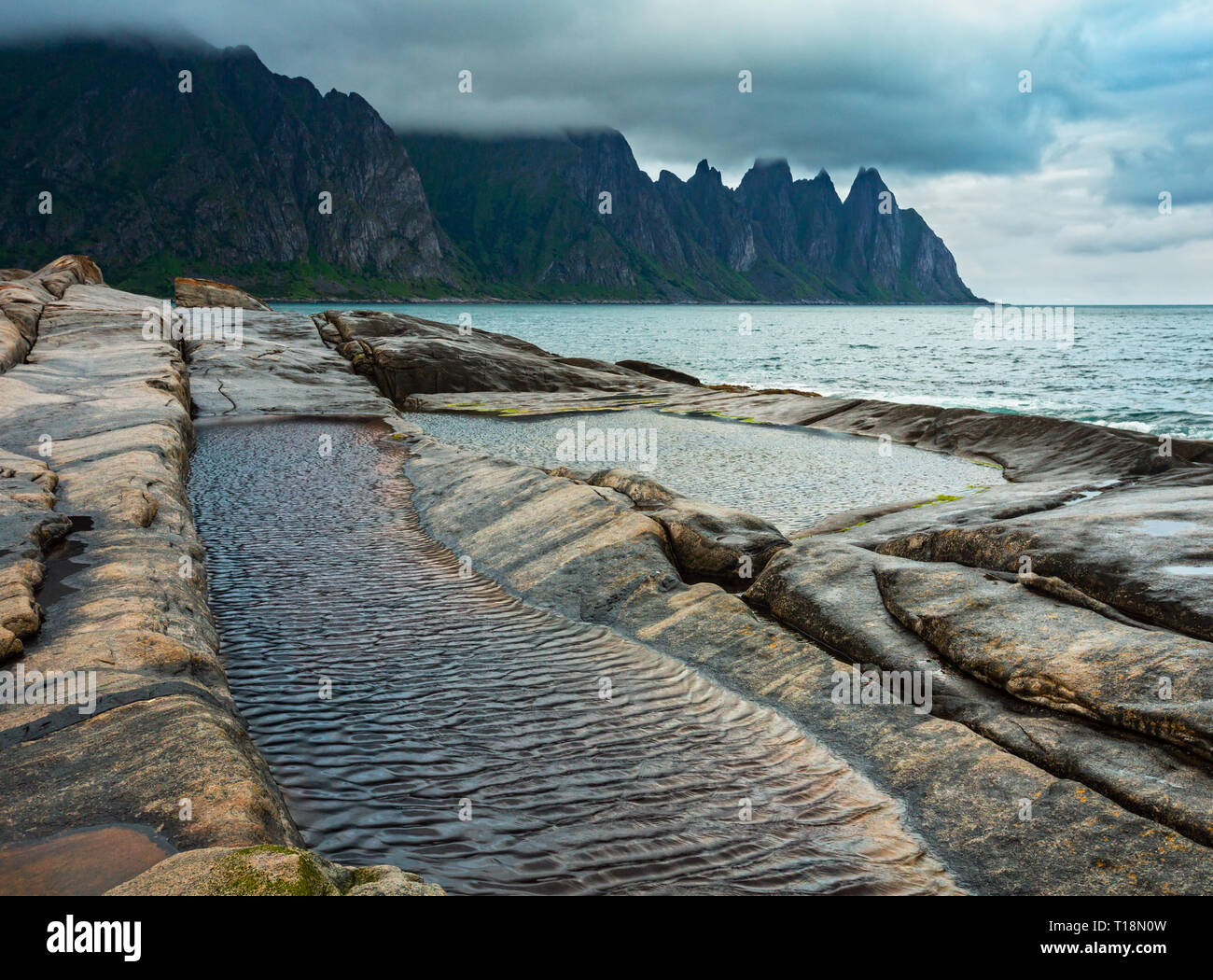 Stony beach with tidal baths at Ersfjord, Senja, Norway. Summer polar ...
