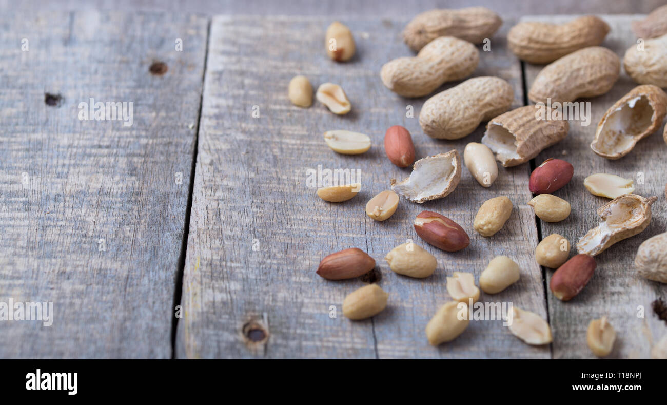 Peanuts scattered on natural wooden desk Stock Photo - Alamy