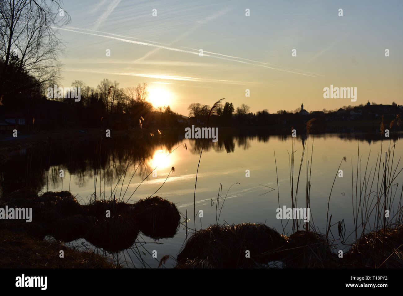 Bavarian lake in the golden hour. The last sun rays are shining trough ...