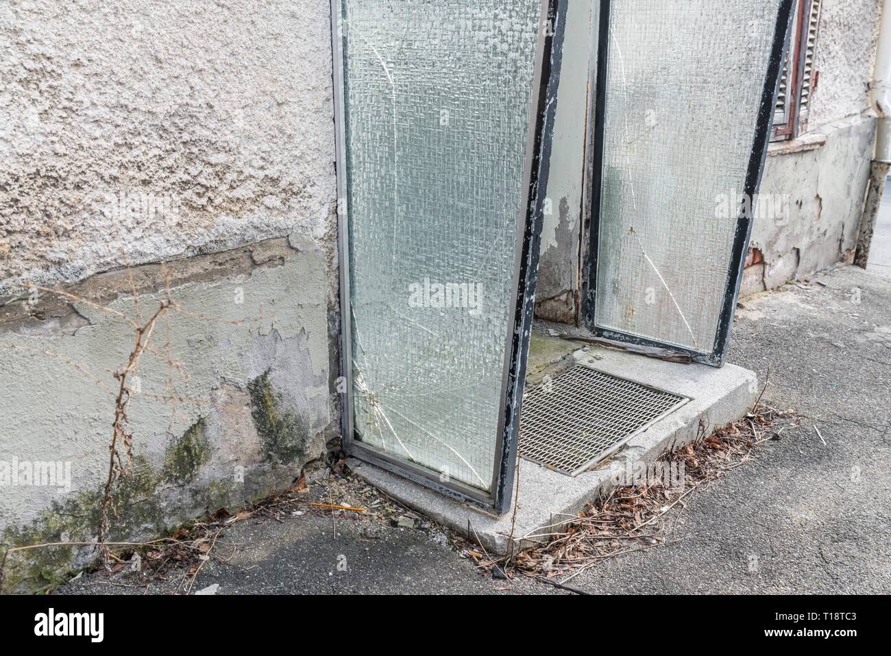 Old broken entrance area of a front door with glass walls and glass ...