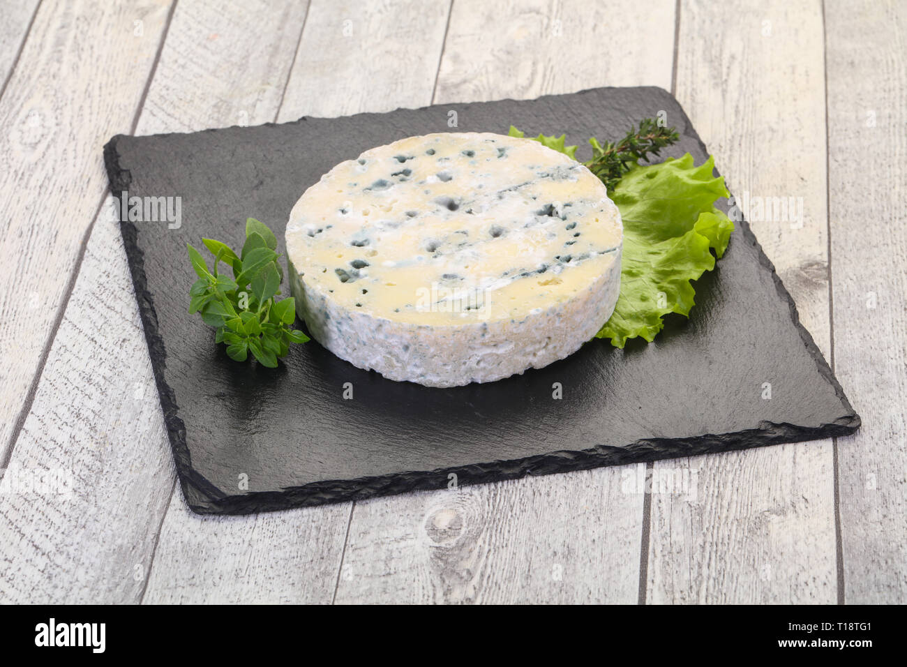 Round blue cheese with salad and basil Stock Photo - Alamy