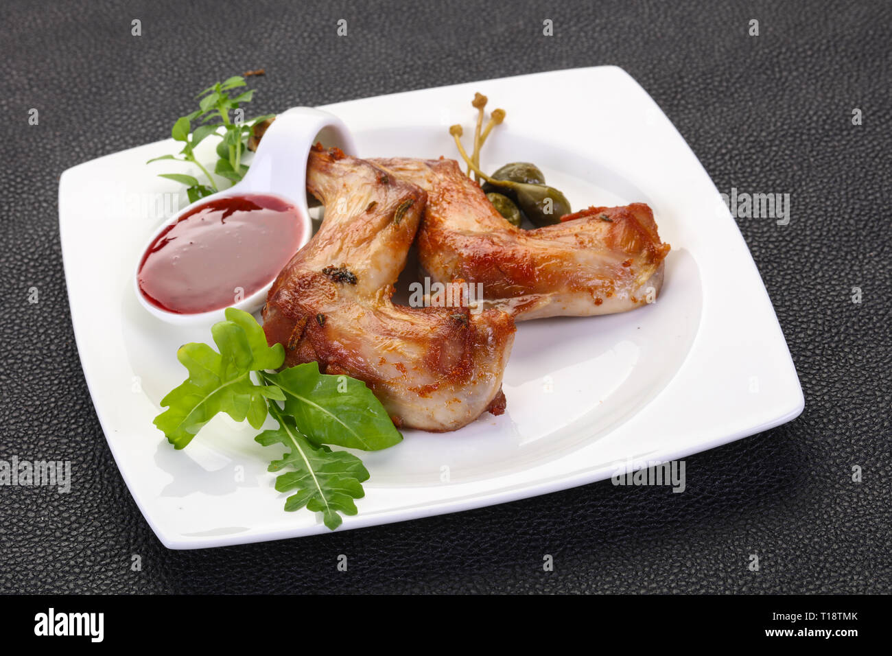 Roasted rabbit legs with cowberry sauce Stock Photo - Alamy