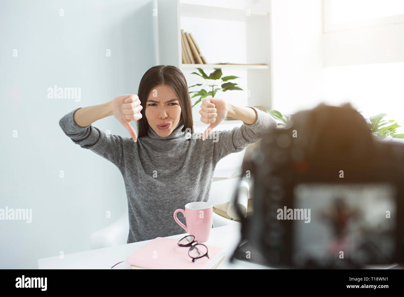 Very angry female person is looking to th camera and showing her thumbs ...