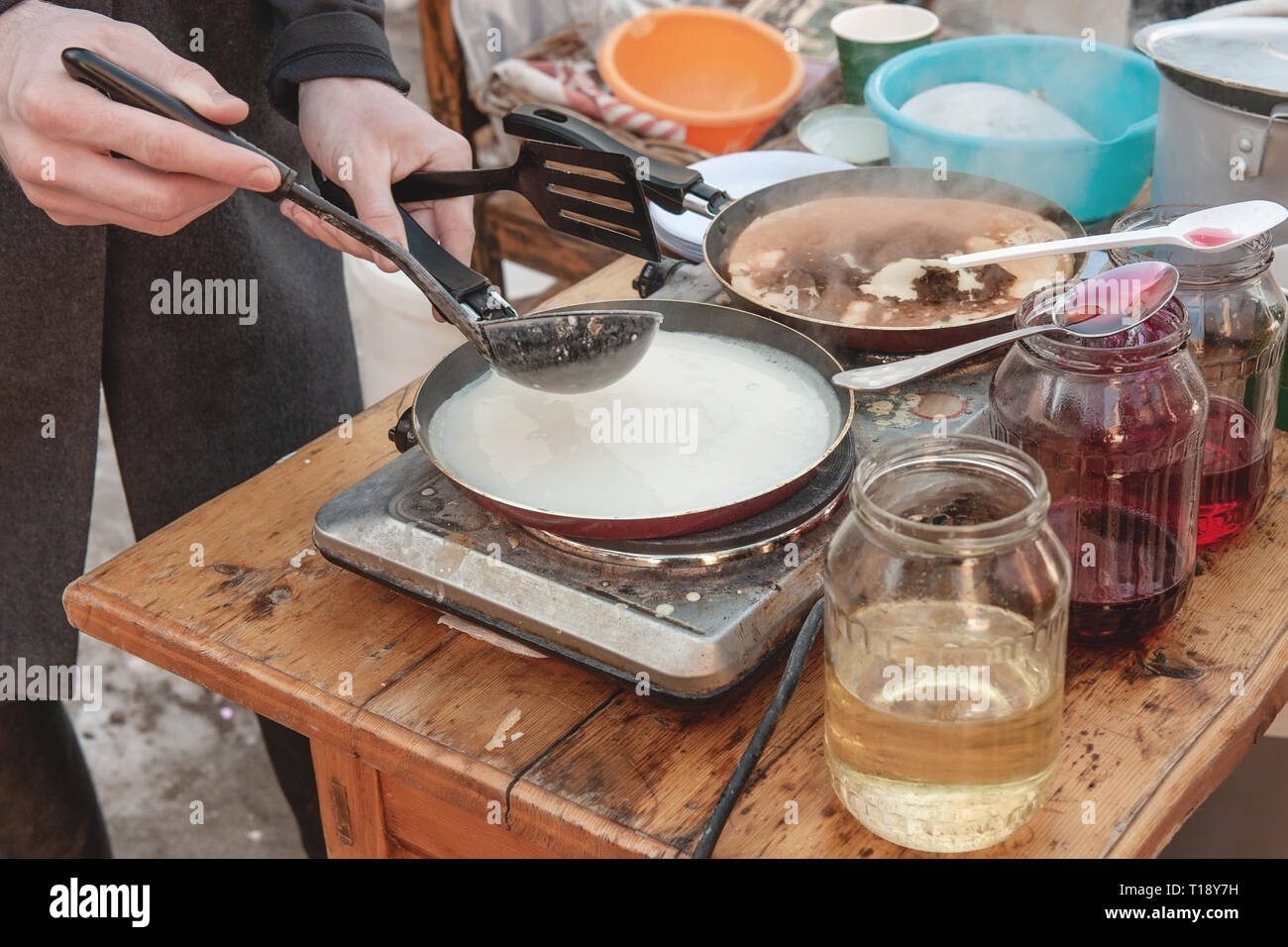 Cooking pancakes outside in the cold. Pancakes are fried in a pan and ...