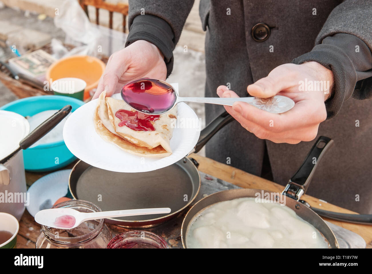 Cooking pancakes outside in the cold. Pancakes are fried in a pan and ...