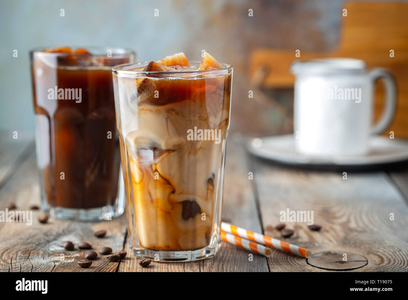 Ice coffee in a tall glass with cream poured over, coffee ice cubes and ...