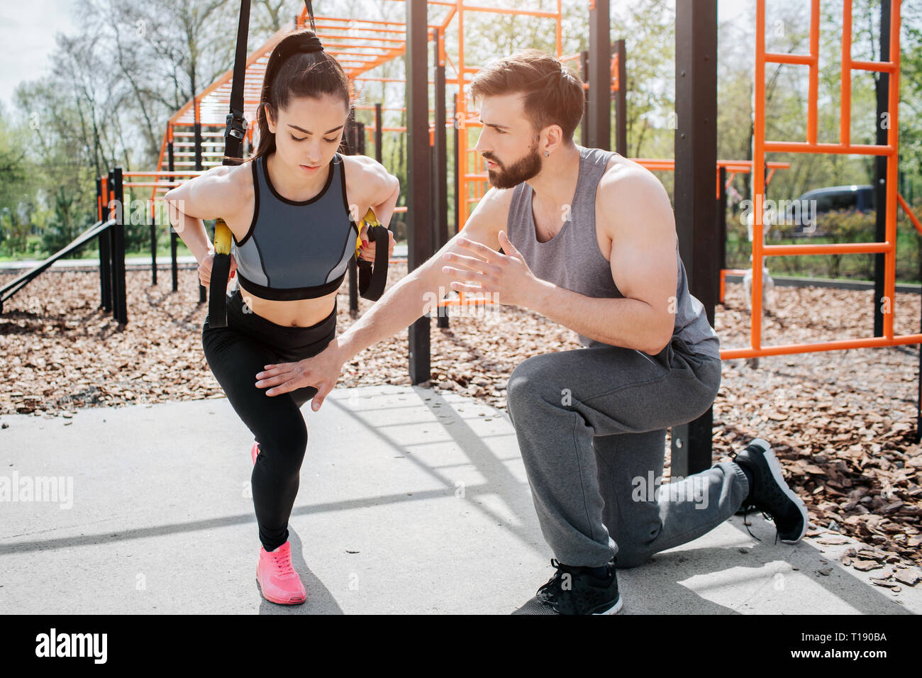 Two beautiful people are exercising. Girl is holding loops with her ...