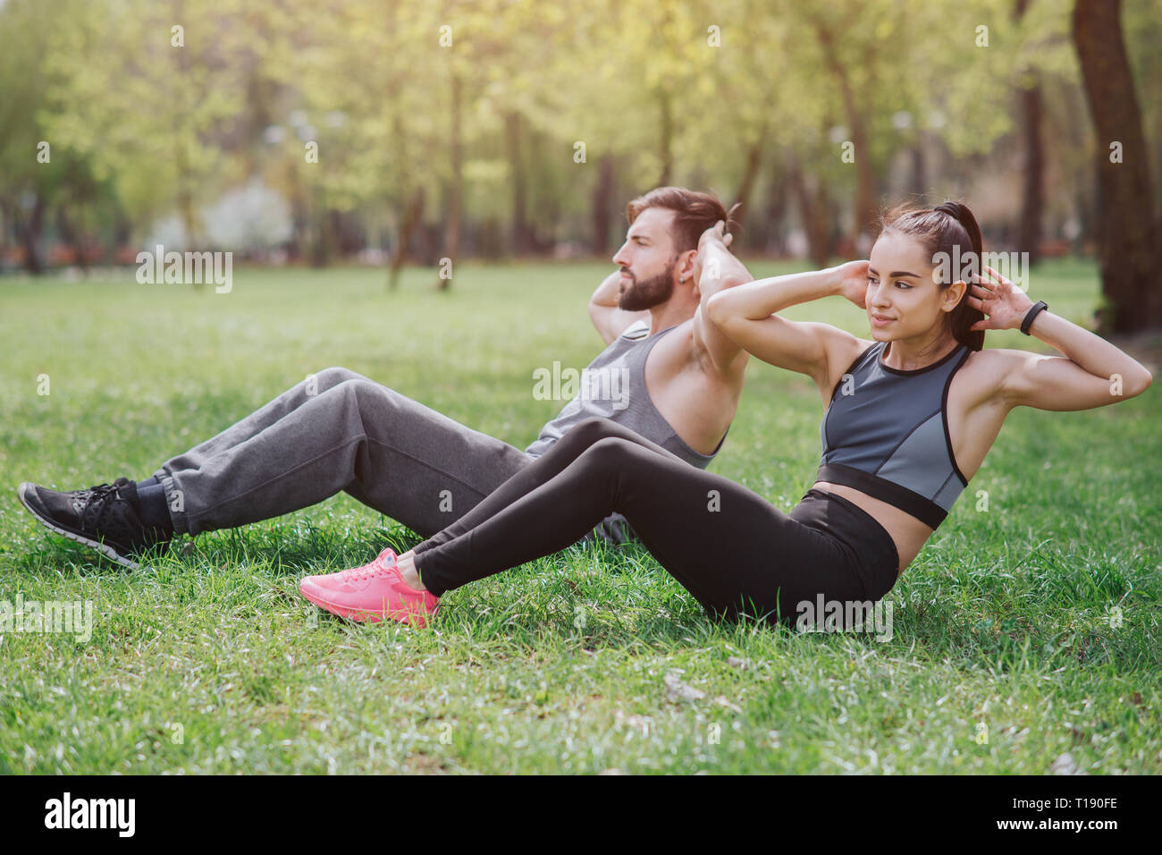 Strong and powerful people are working out outside in park. They are ...