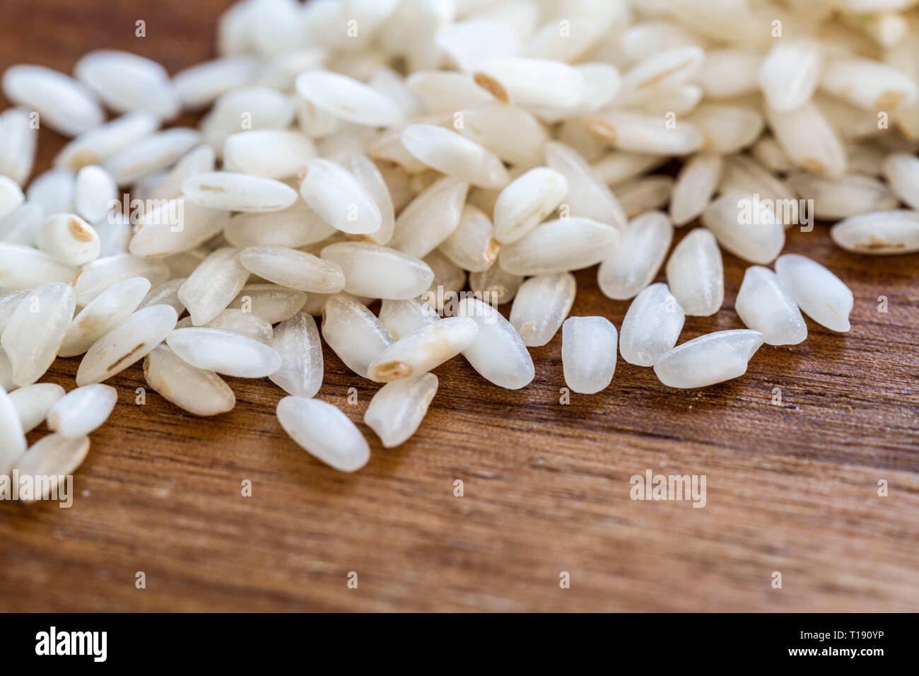 Close up of white raw rice on a wooden table Stock Photo - Alamy