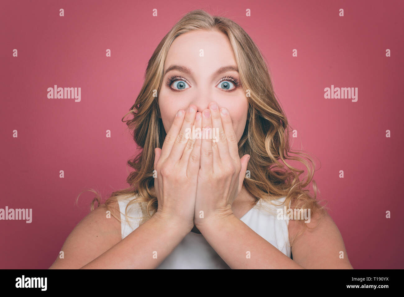 Attractive firl is looking straighht forward and covering her mouth ...