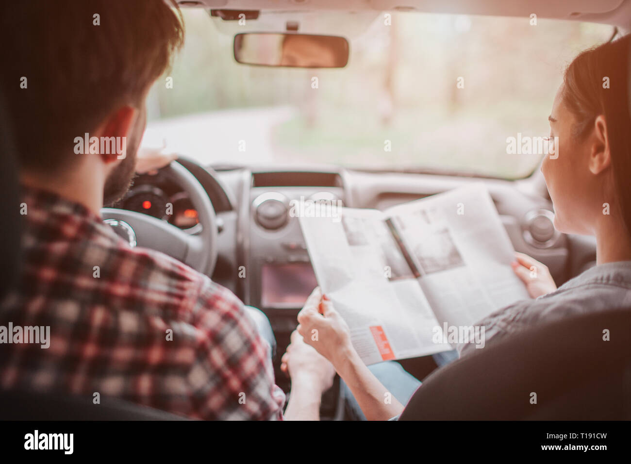 Young couple is travelling. They are riding in car. Girl holds map and ...